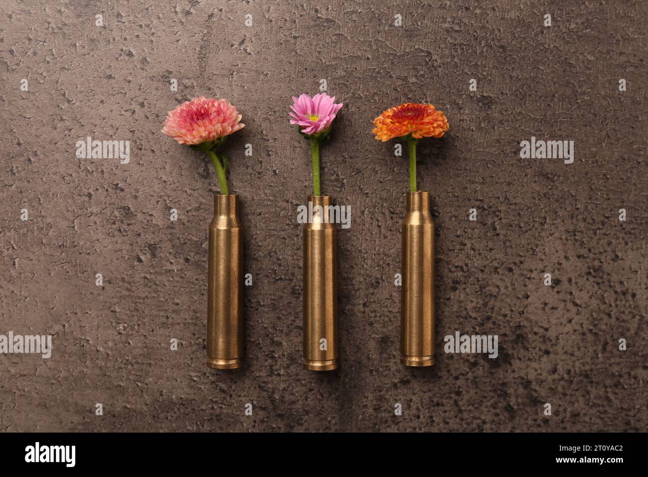 Beautiful flowers in bullet cases on grey textured table, flat lay ...