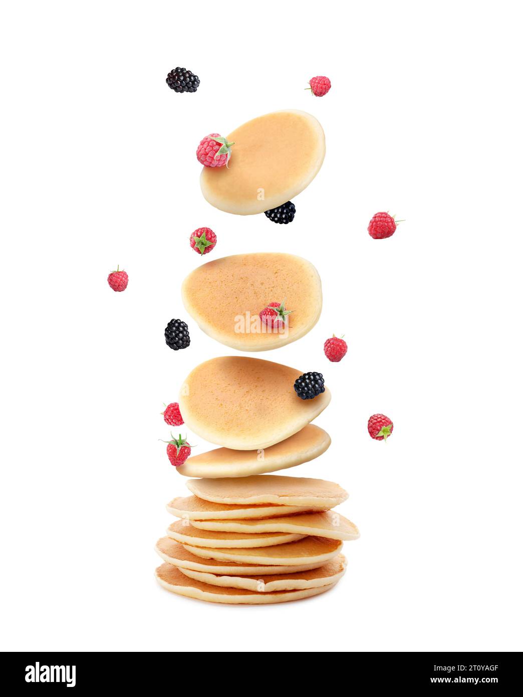 Many fresh pancakes and berries falling onto stack against white ...