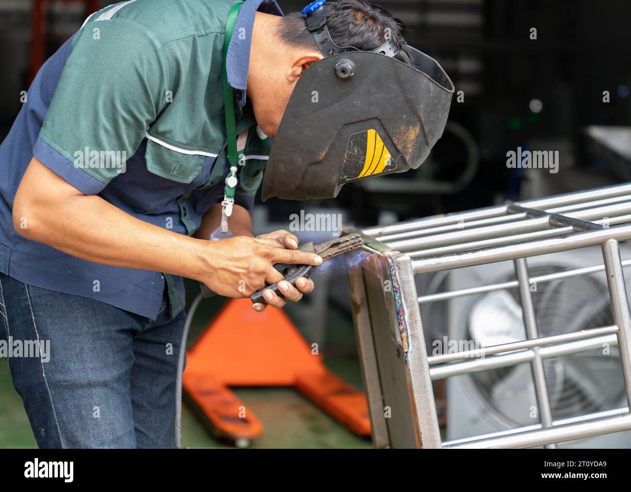 The mechanic bent down to weld the base of the stainless steel ...