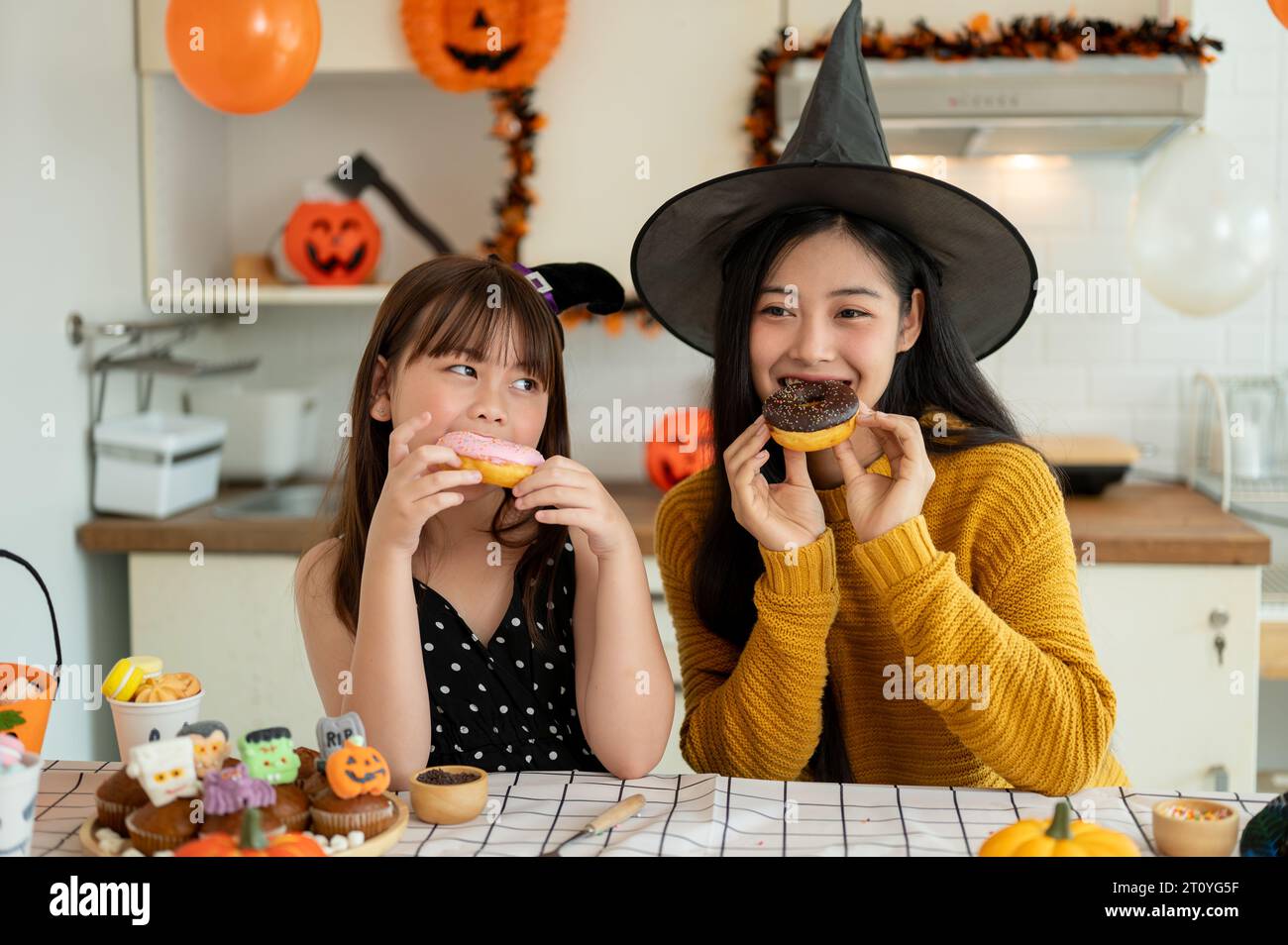 A cheerful and cute young Asian girl in a Halloween costume enjoys ...