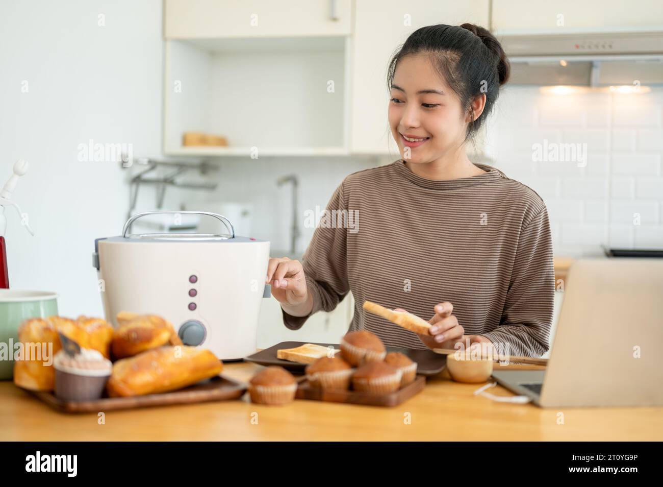 A beautiful and happy young Asian woman is making tasty toasts with a ...