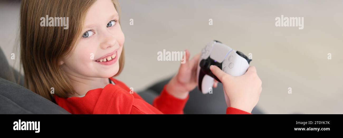 Cute little girl holds gaming console looking in camera Stock Photo - Alamy