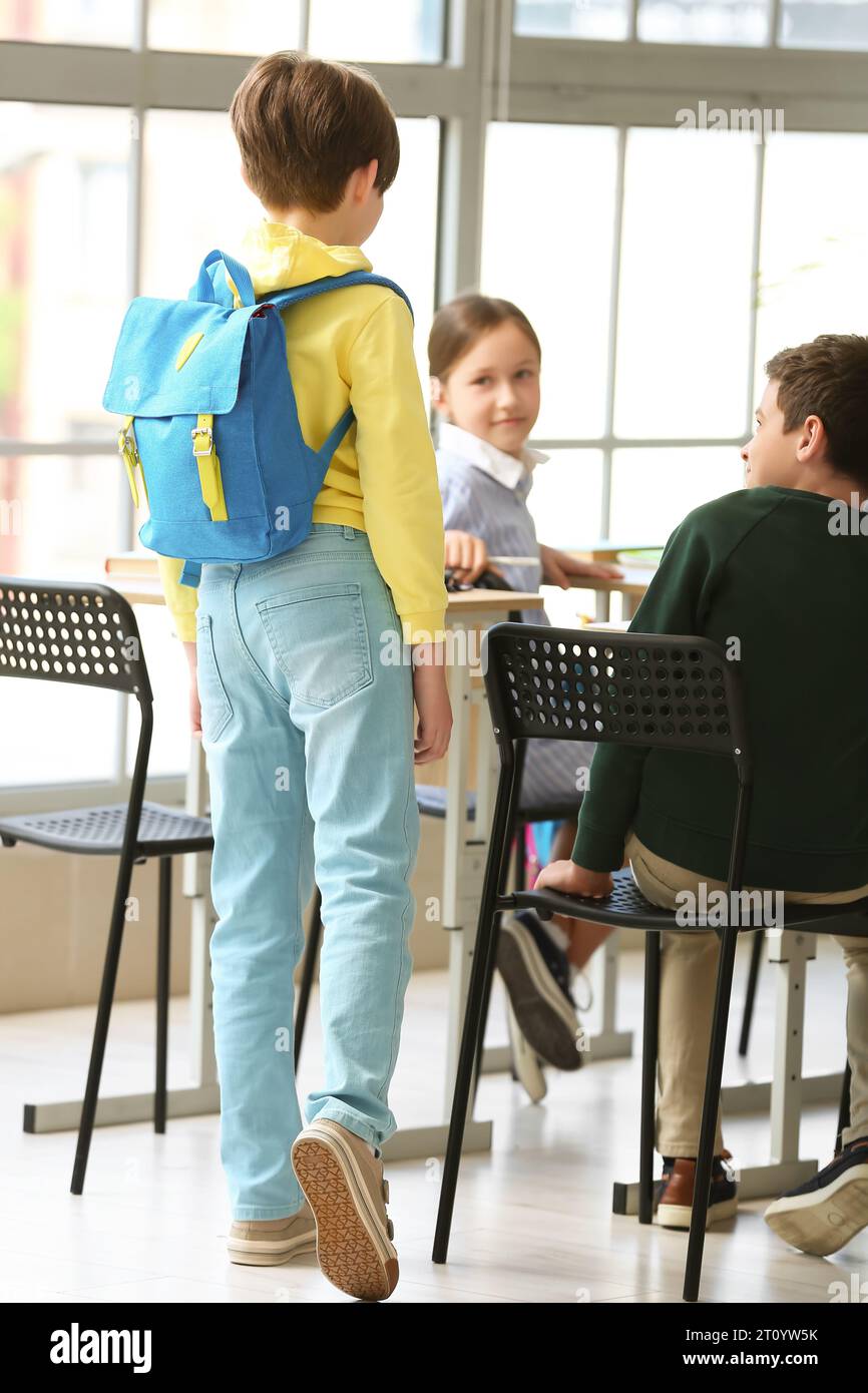 Little boy with backpack in classroom, back view Stock Photo - Alamy