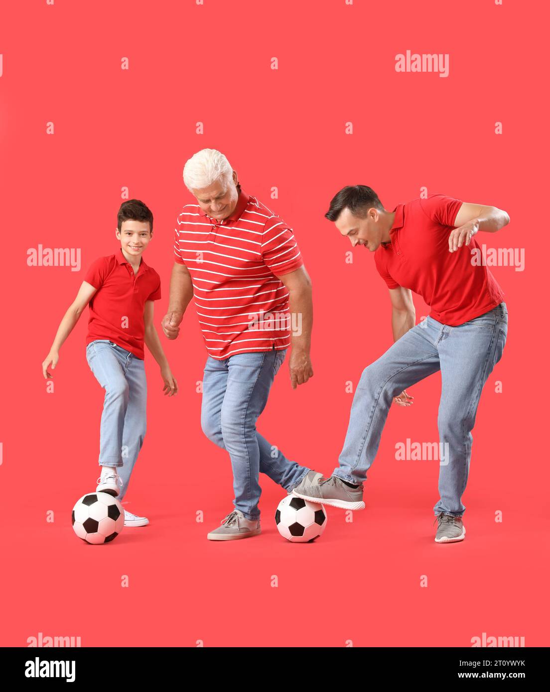 Little boy with his dad and grandfather playing football on red ...