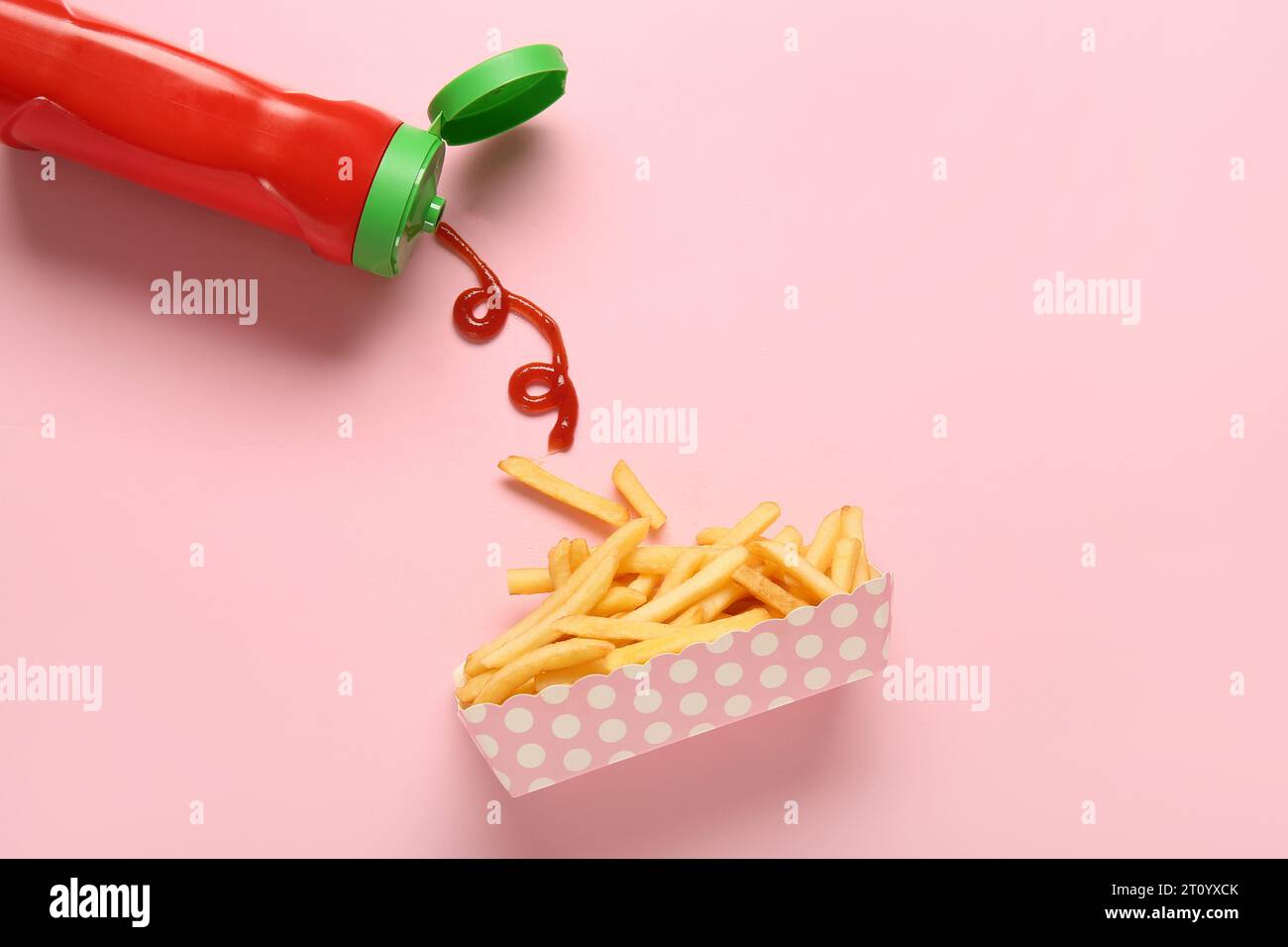 Paper box with tasty french fries and bottle of ketchup on pink ...