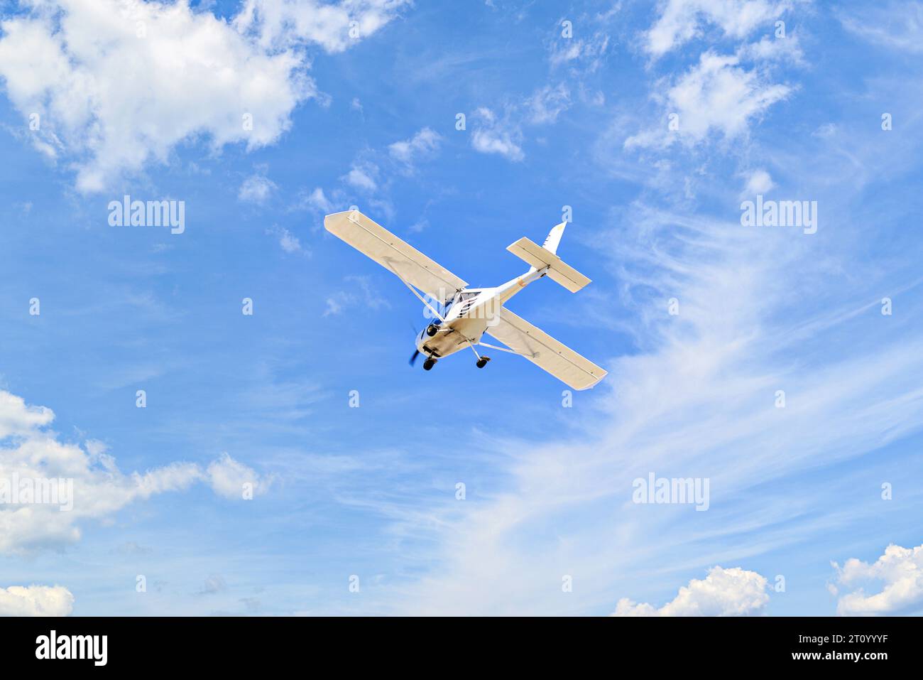 Single engine ultralight plane flying in the blue sky with white clouds ...