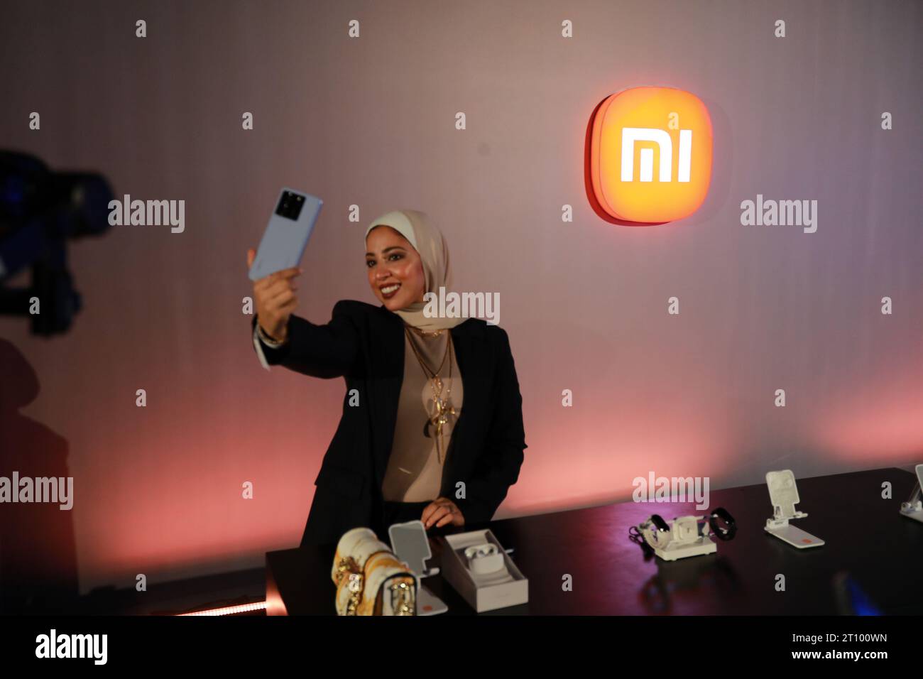 Cairo, Egypt. 8th Oct, 2023. A guest poses for a photo with a Xiaomi 13T smartphone during a ...