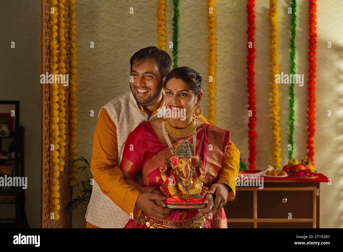 Happy Maharashtrian couple holding statue of Hindu god Ganesh on the ...