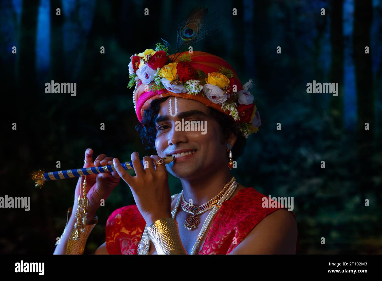 Close-up portrait of young man dressed up as Lord Krishna and playing ...