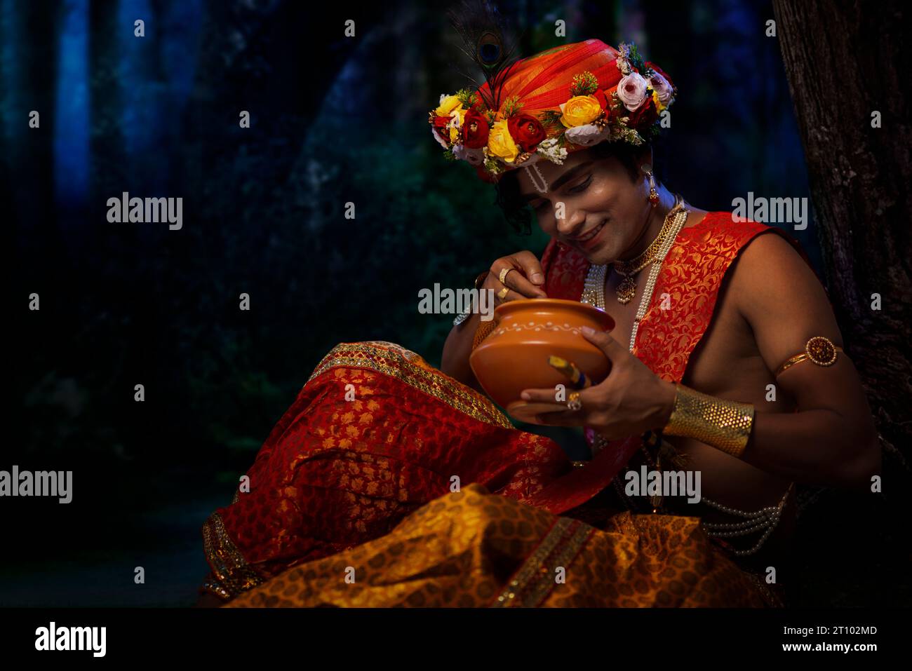 Young man dressed up as Lord Krishna eating makhan on the occasion of ...