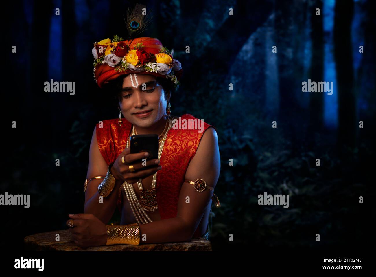 Young man dressed up as Lord Krishna and using mobile phone Stock Photo ...