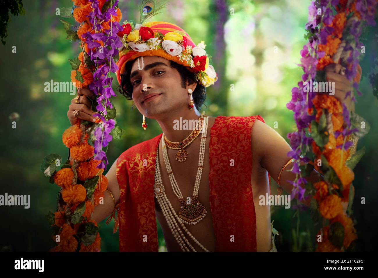 Young man dressed up as Lord Krishna and sitting on a swing on the ...