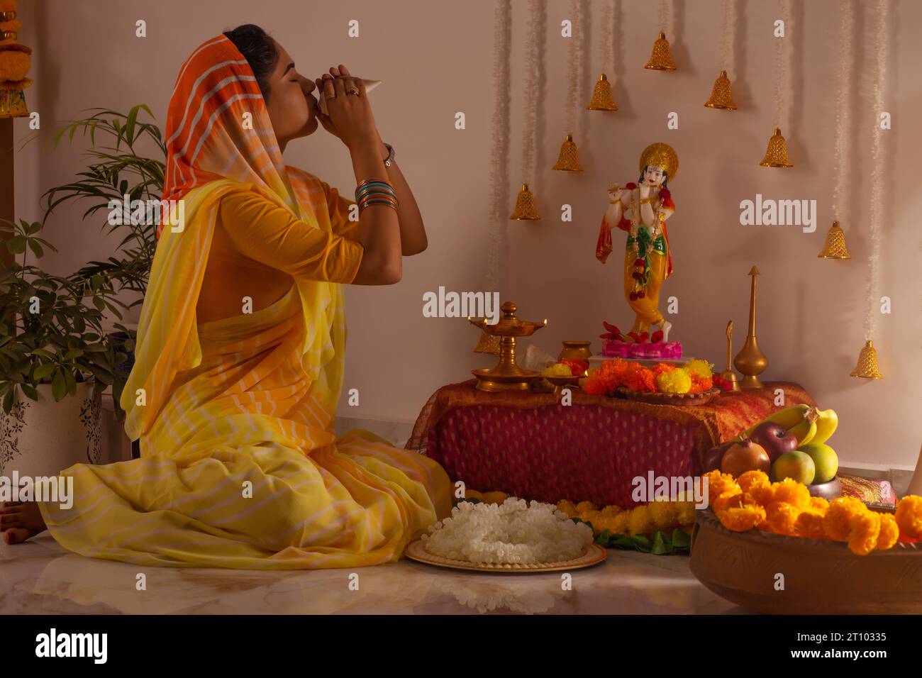 Woman playing conch while worshipping Lord Krishna on the occasion of ...