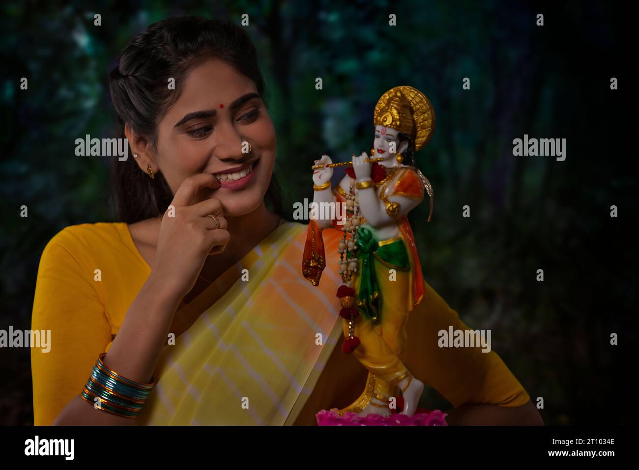 Portrait of woman standing with a statue of Lord Krishna Stock Photo ...