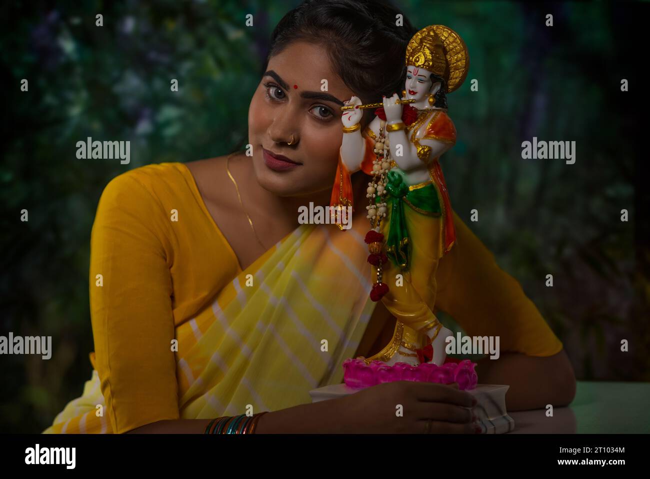 Portrait of woman standing with a statue of Lord Krishna Stock Photo ...
