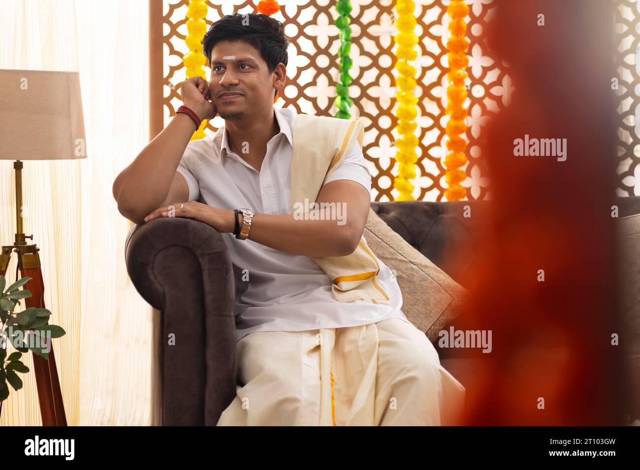 South Indian man sitting on sofa in living room at home Stock Photo - Alamy