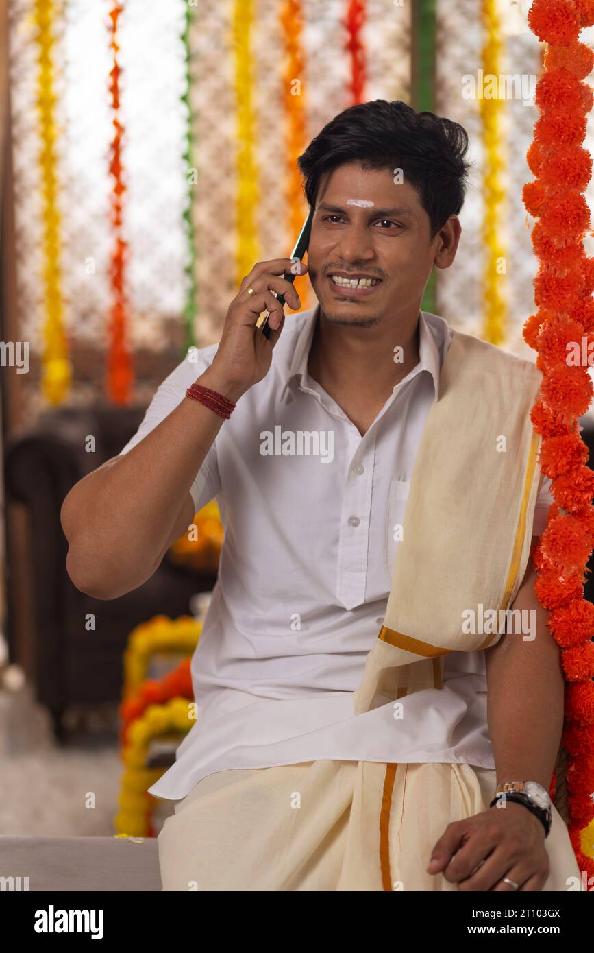 South Indian man talking on mobile phone while sitting on a swing Stock ...