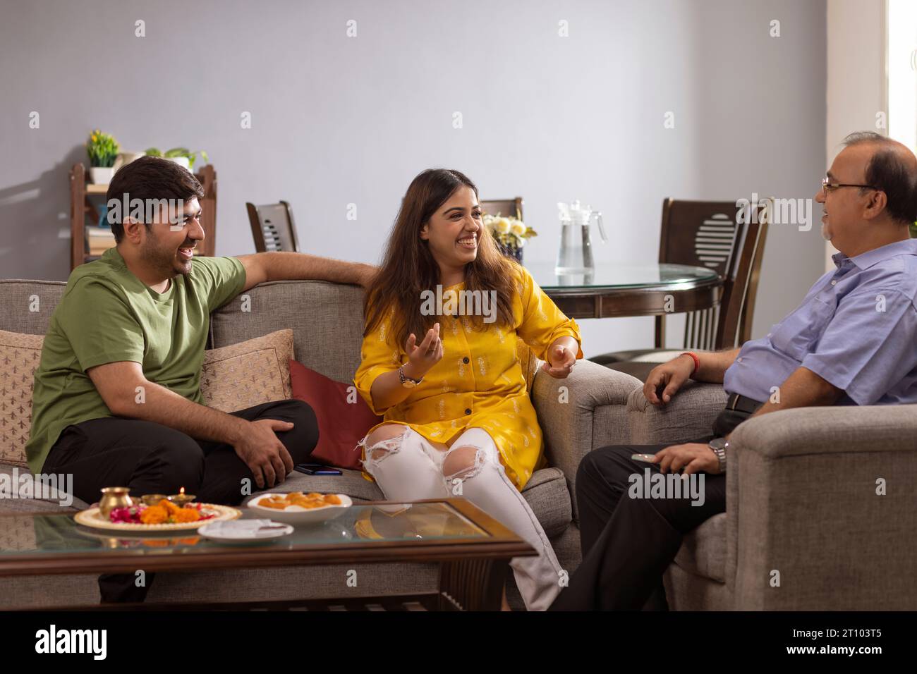 Happy Indian family sitting together at home and talking to each other ...