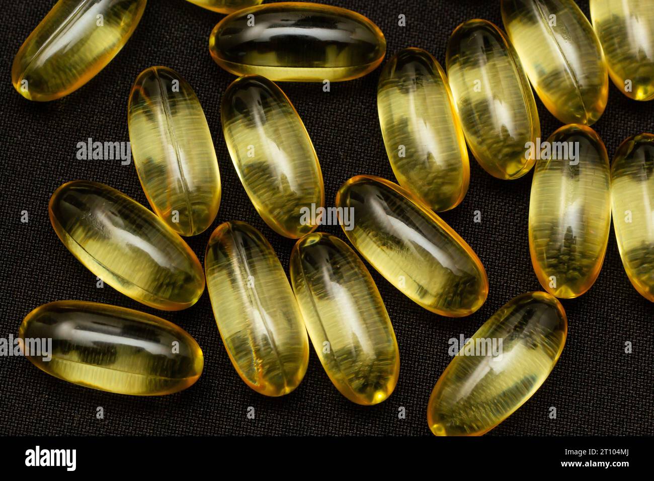 Macro Close up of Omega 3 gel capsule on a reflective black background ...