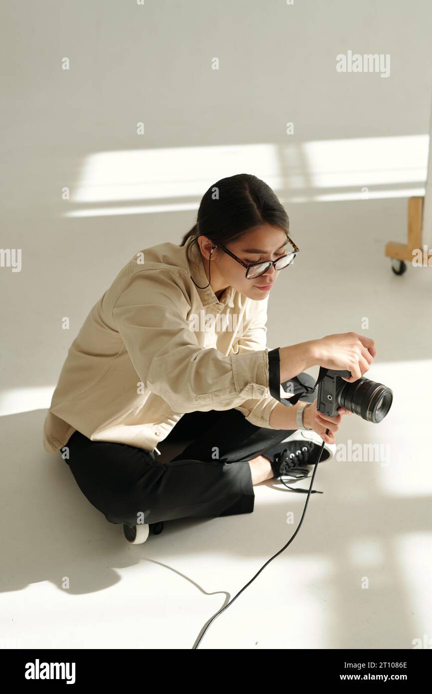 Young professional female photographer adjusting settings of ...