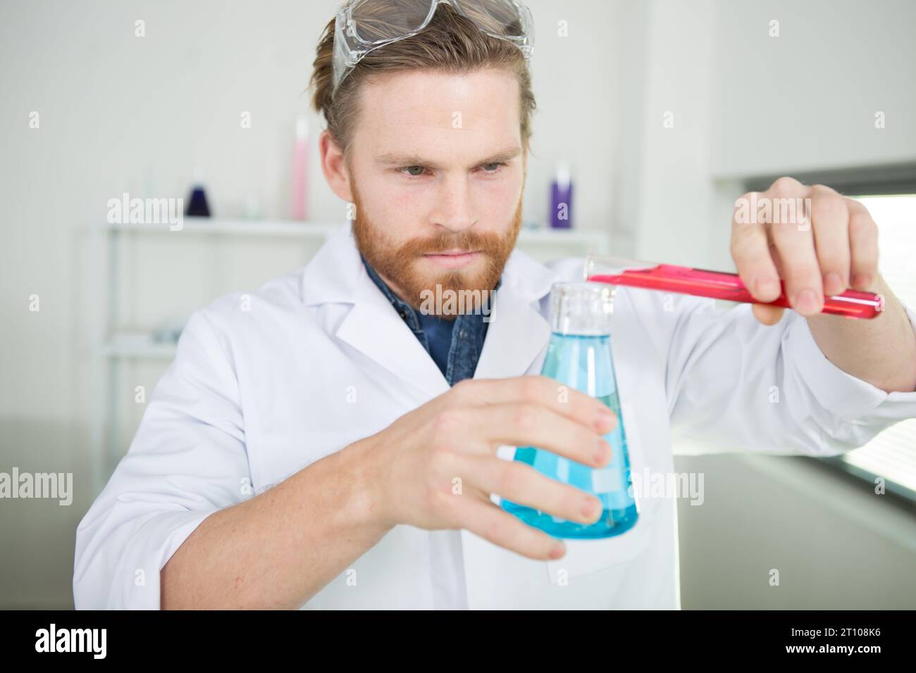 male scientist pouring red liquid from beaker into test tube Stock ...