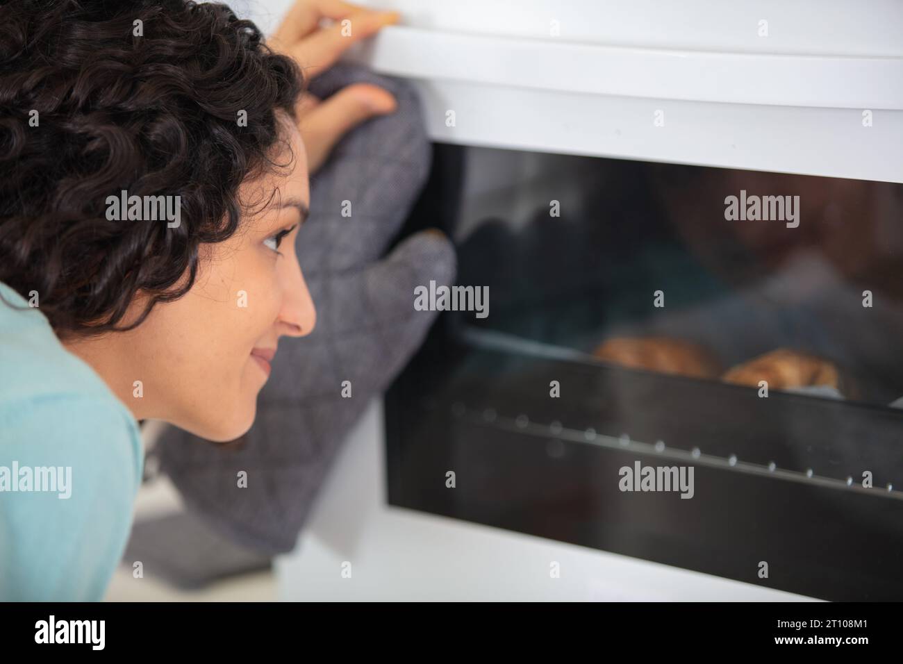 beautiful young woman cooking food in oven Stock Photo - Alamy