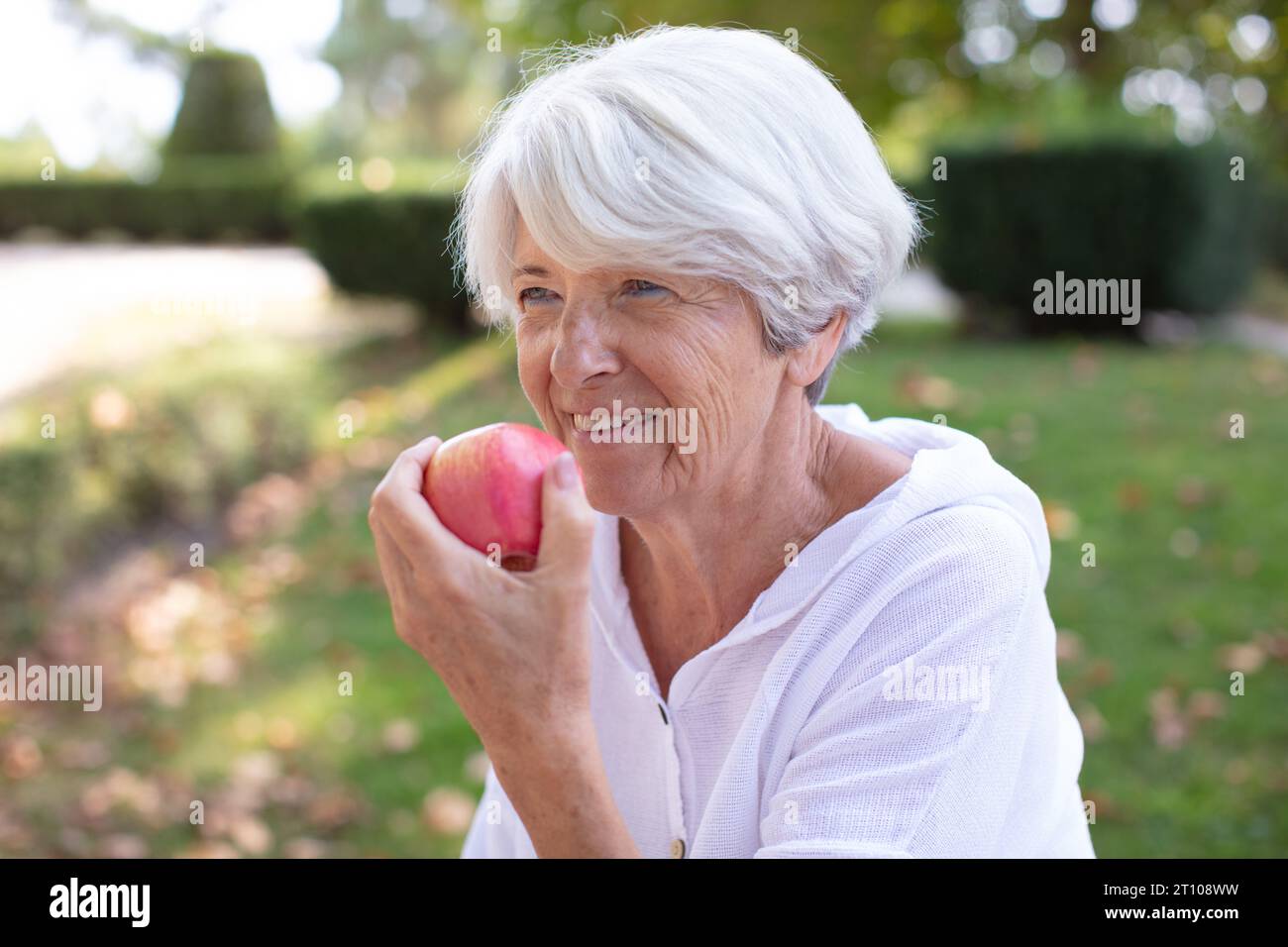 healthy looking senior woman eating apple outside Stock Photo - Alamy