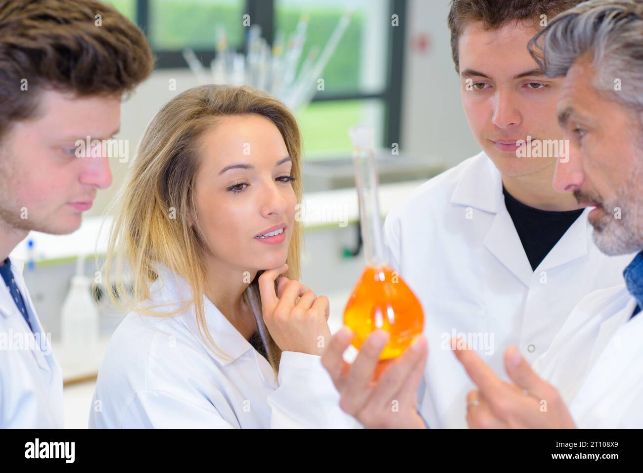 Science students discussing experiment with teacher Stock Photo - Alamy