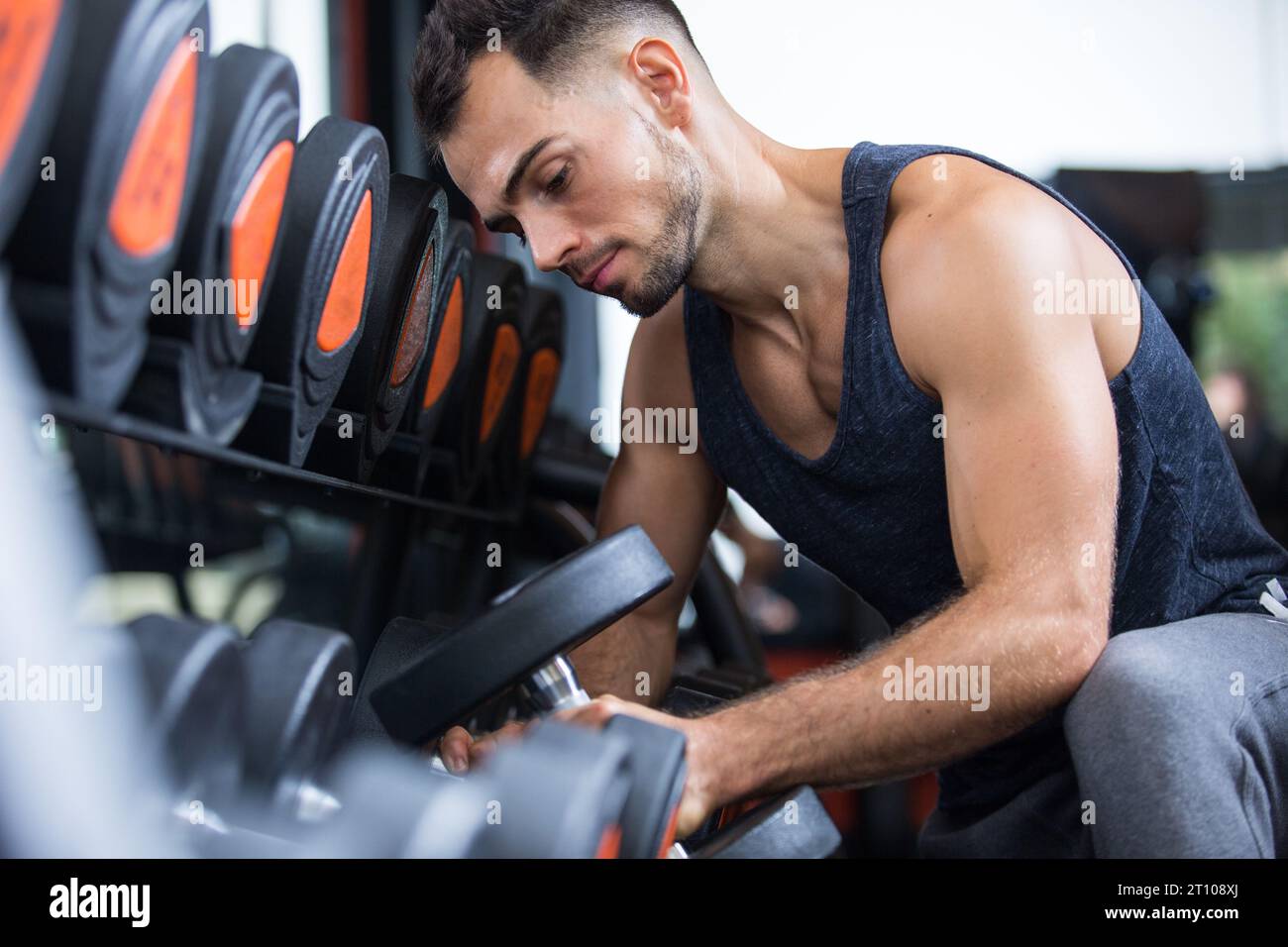 man picking up a dumbbell Stock Photo - Alamy
