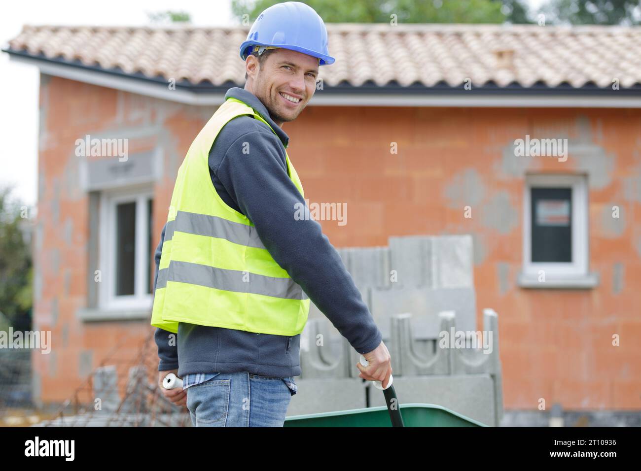 worker pushing a wheelbarrow full of bricks Stock Photo - Alamy