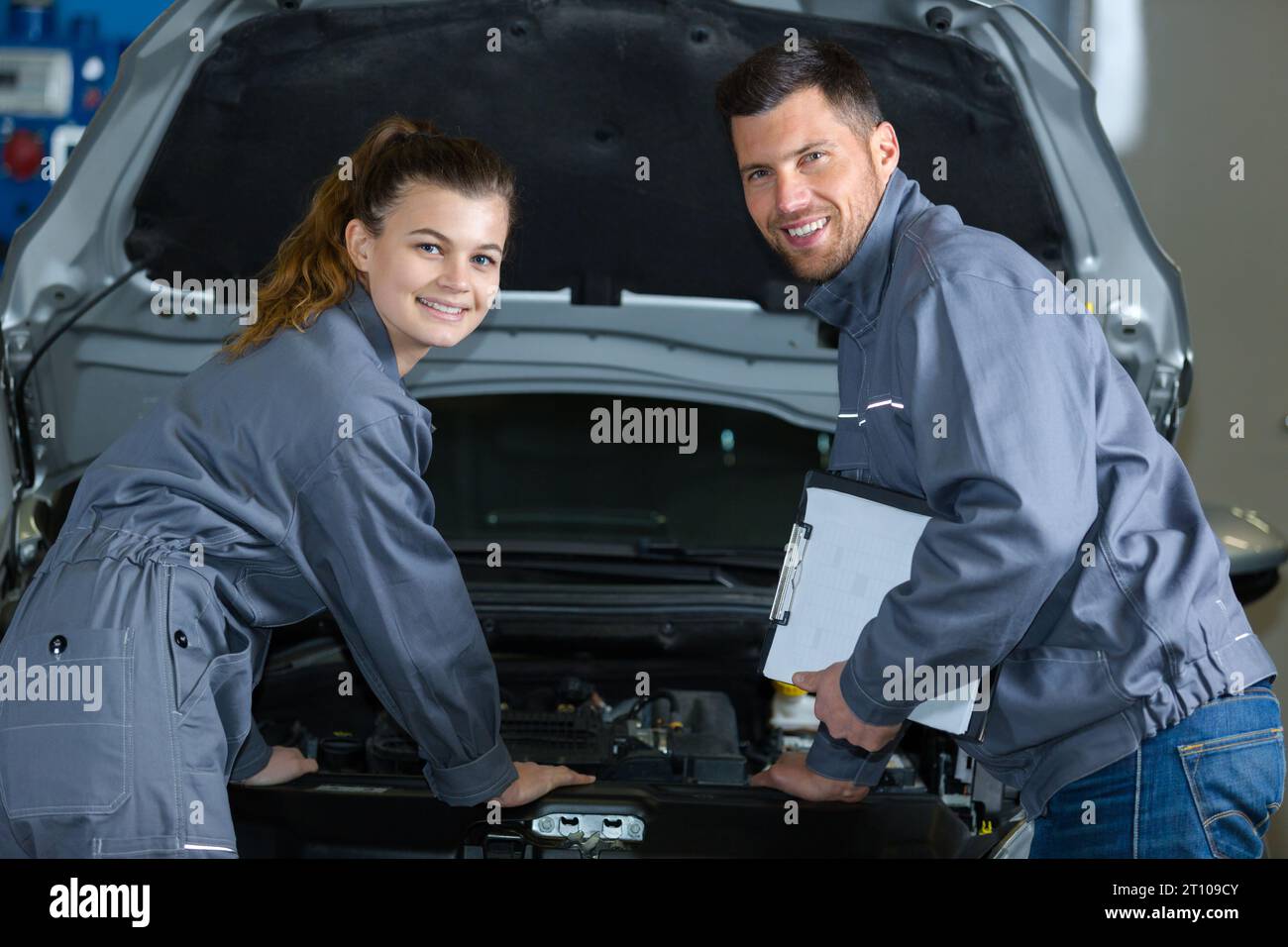 mechanic with female apprentice by car with bonnet raised Stock Photo ...