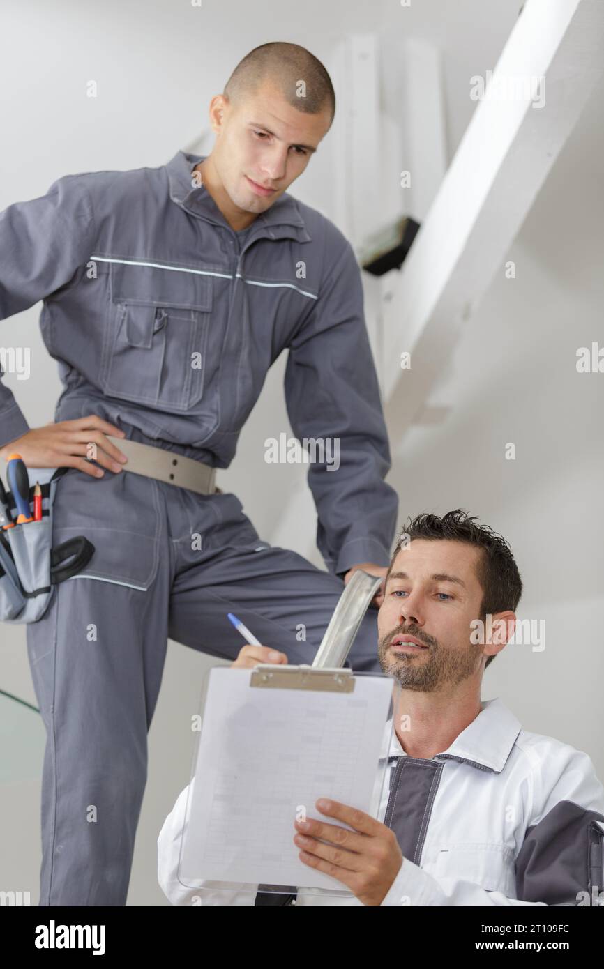 skilled painter with apprentice looking at clipboard Stock Photo - Alamy