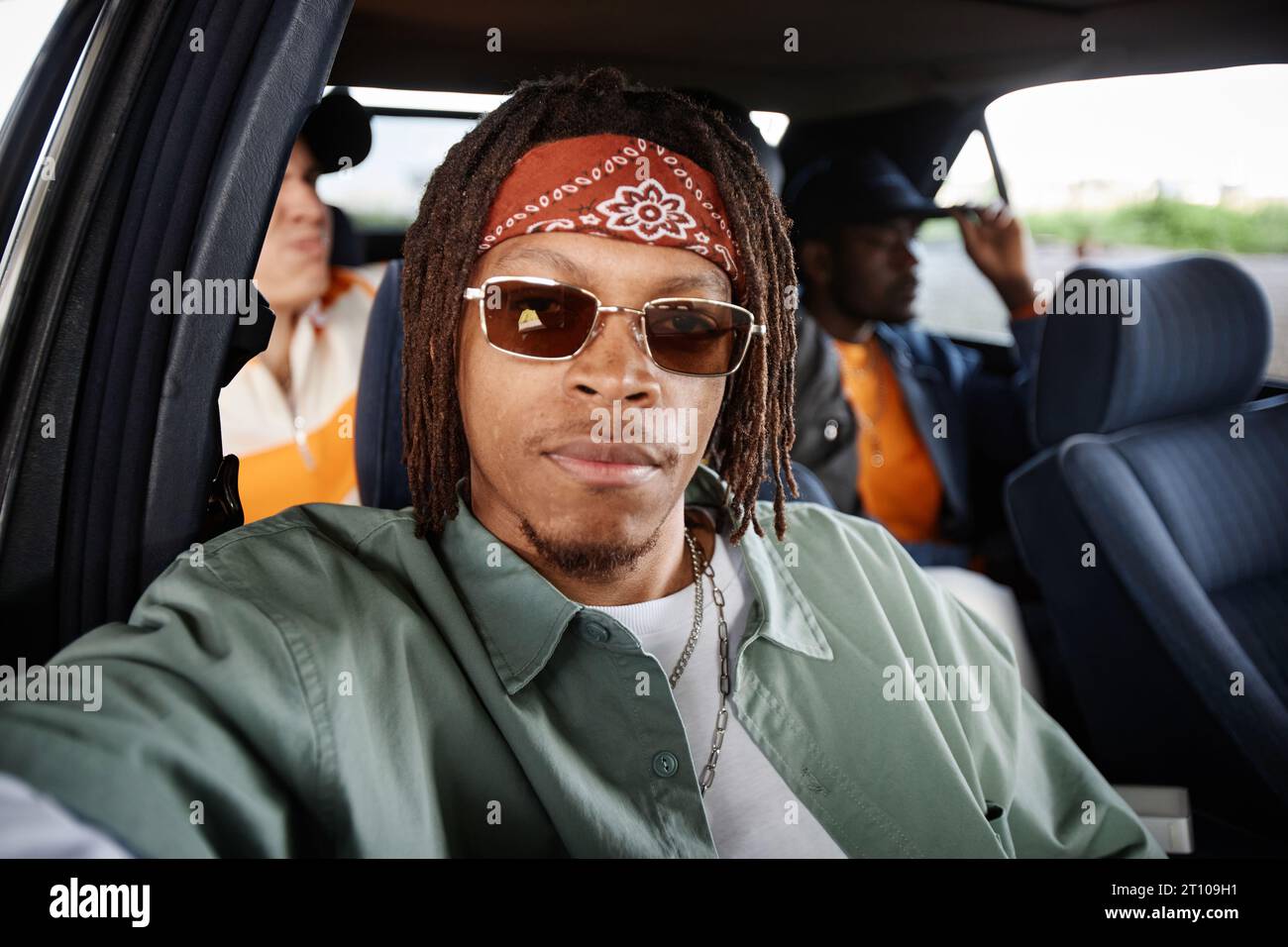 Serious African American guy with dreadlocks sitting by window in car ...