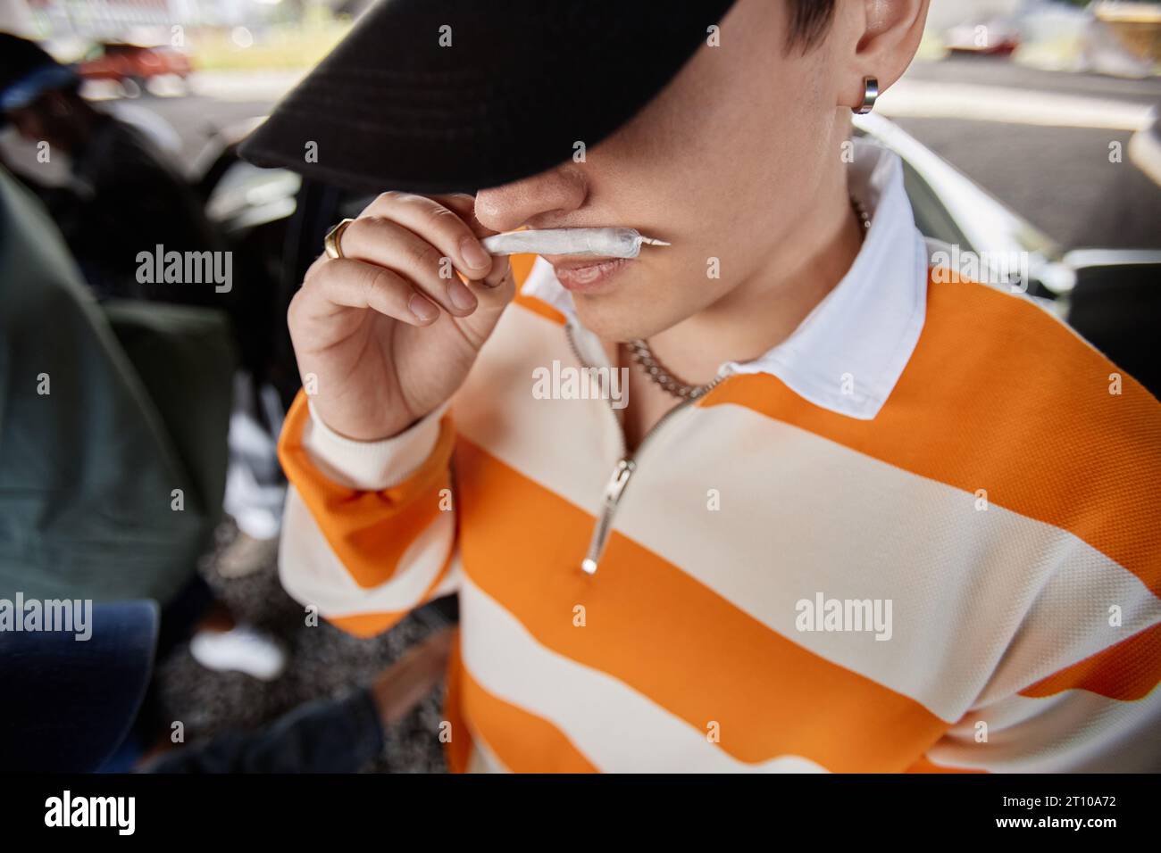Close-up of young stylish male hip hop dancer in black cap and striped ...