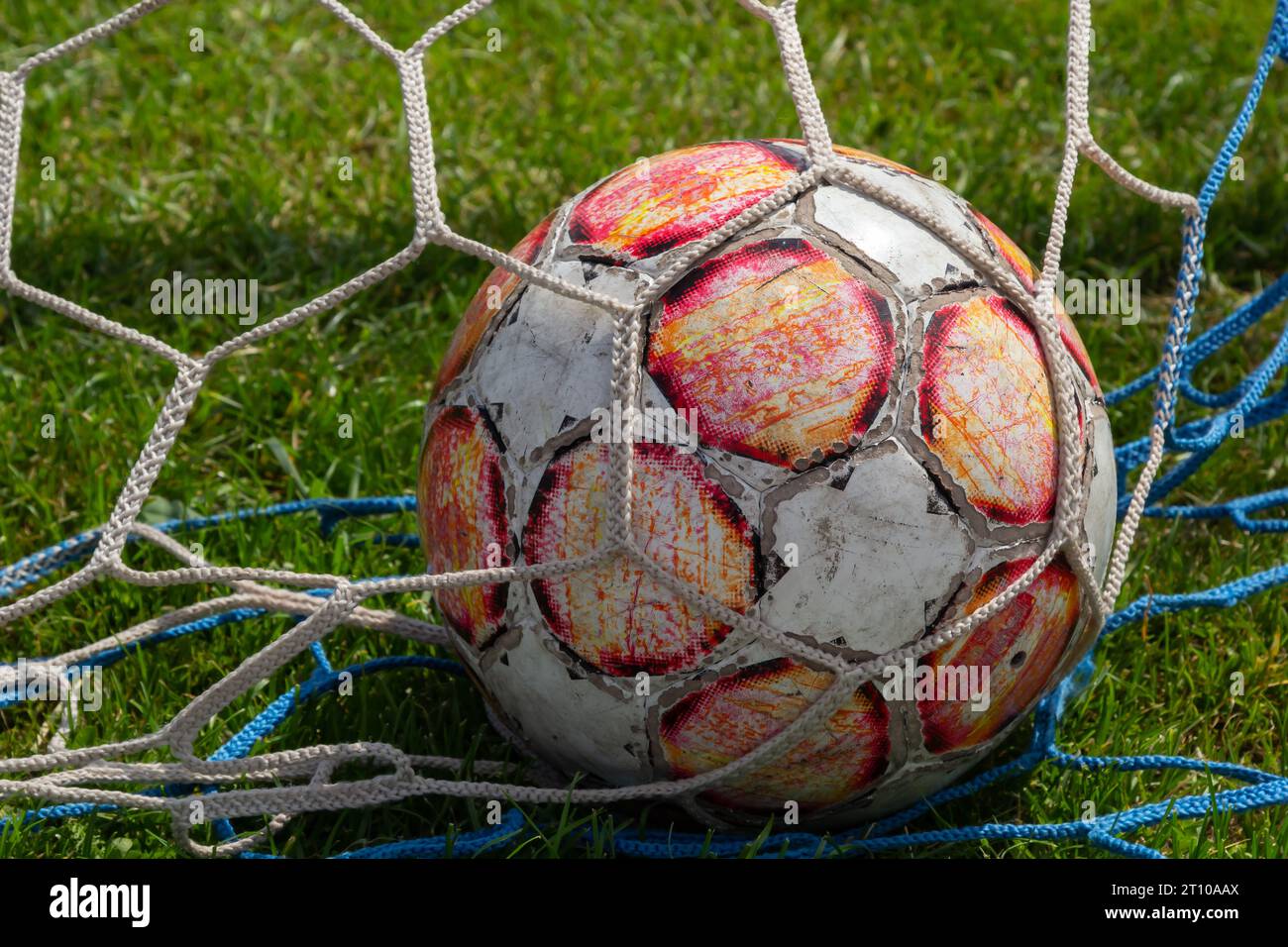 old soccer ball in the net on the background of grass soccer field ...