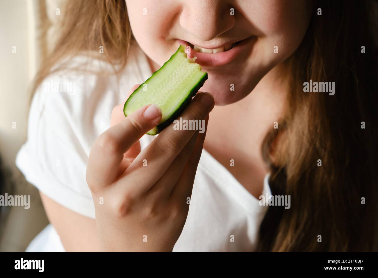 Kid bites cucumber, close-up, unrecognizable face. Girl eating cucumber ...