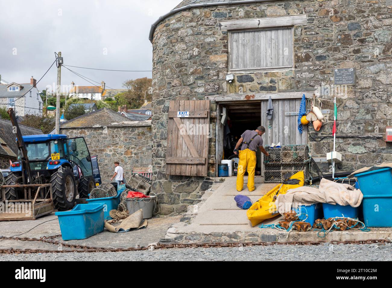 Cadgwith Cove fisherman in oil skins working at the fishing hut ...