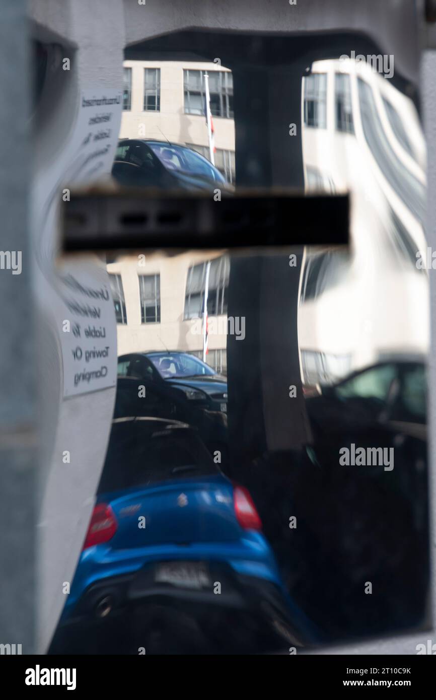 Distorted reflection of city buildings and cars in a broken mirror ...