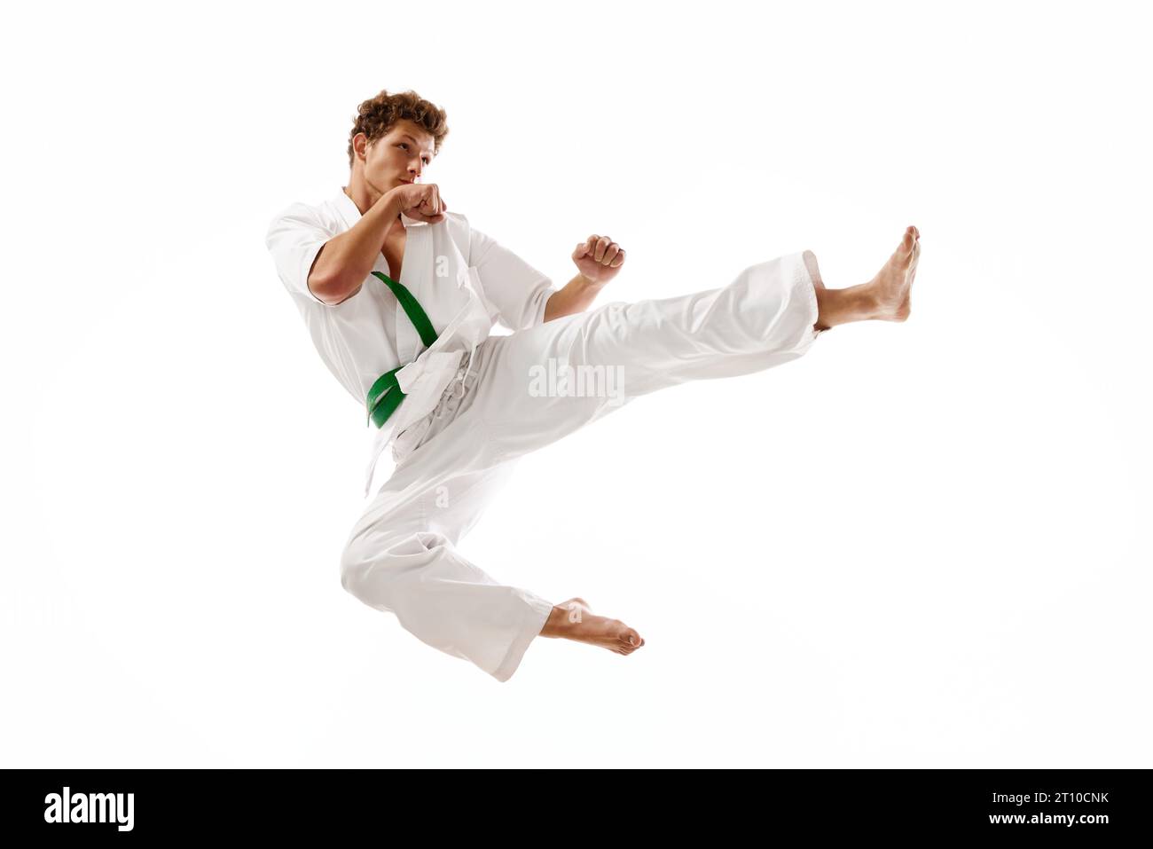Kick in a jump. Young athletic man, karateka in motion training ...