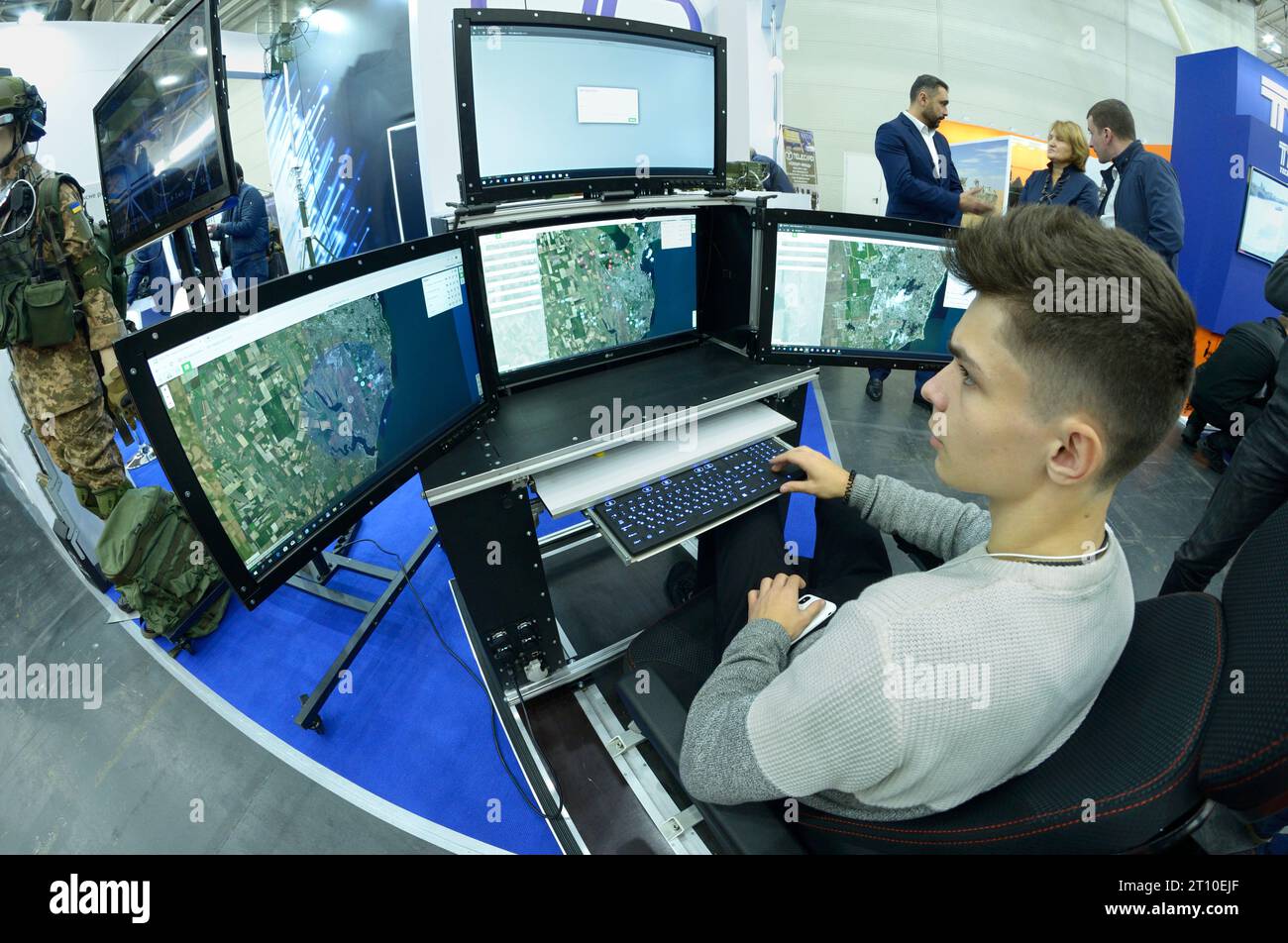 Young man sitting in front of monitors and working with military ...