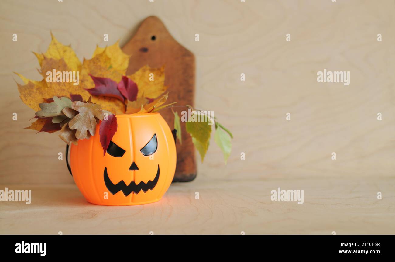 Happy Halloween. Plastic pumpkin bucket with an evil smile and autumn ...