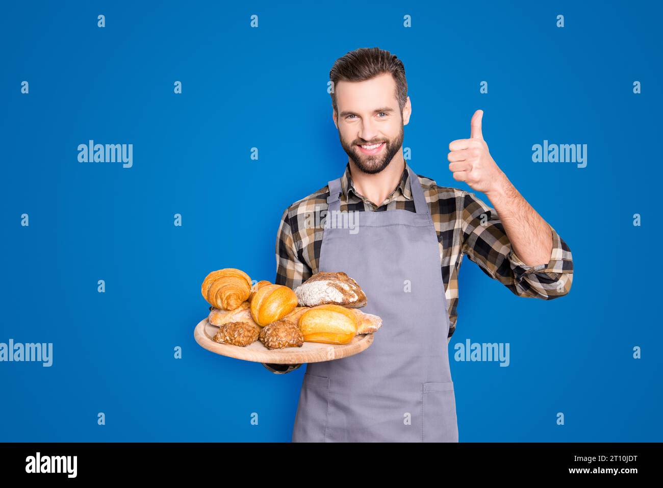 Portrait of positive attractive baker in uniform with stubble holding ...