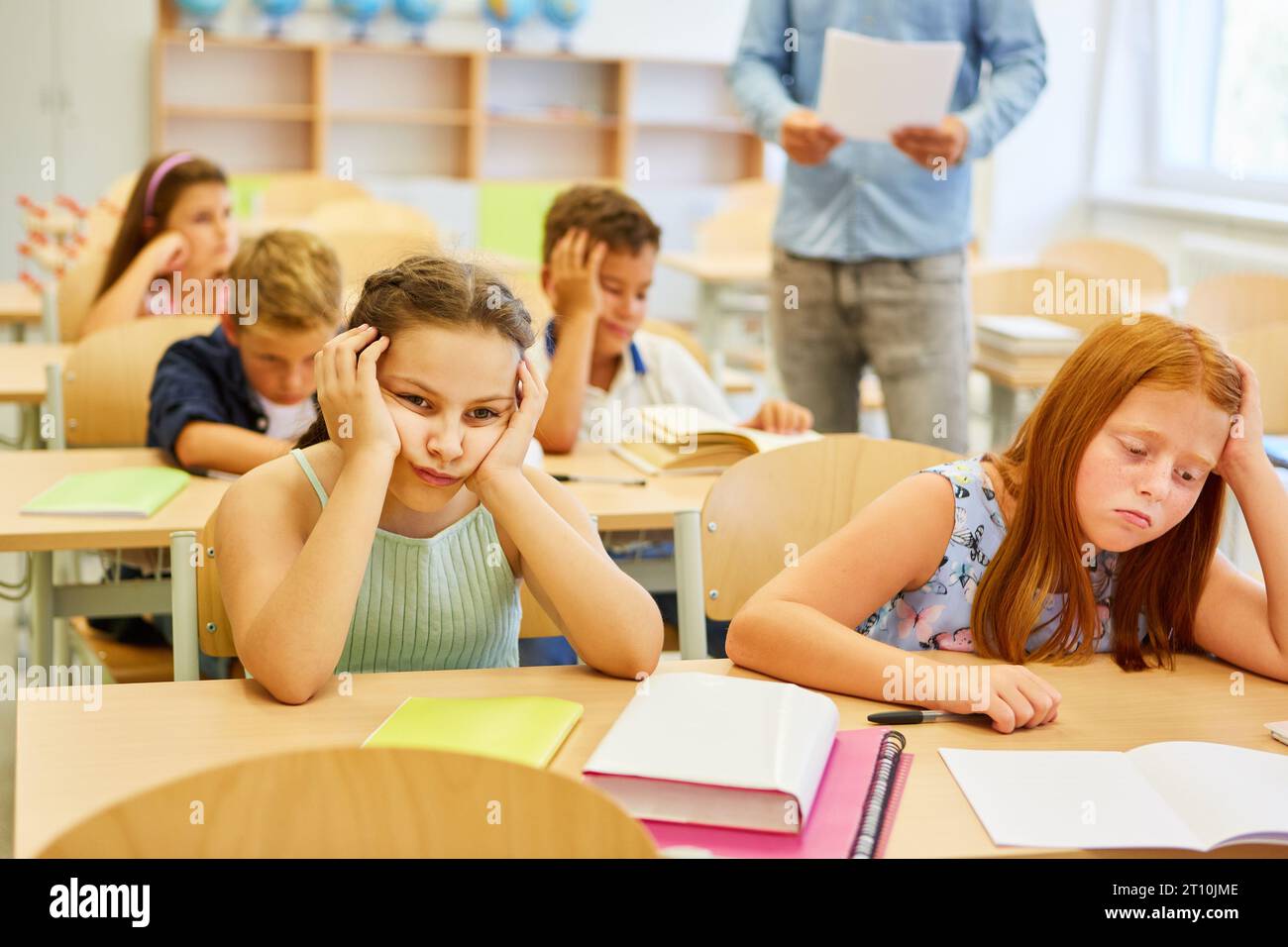 Tired female friends sitting on bench during lecture in classroom Stock ...