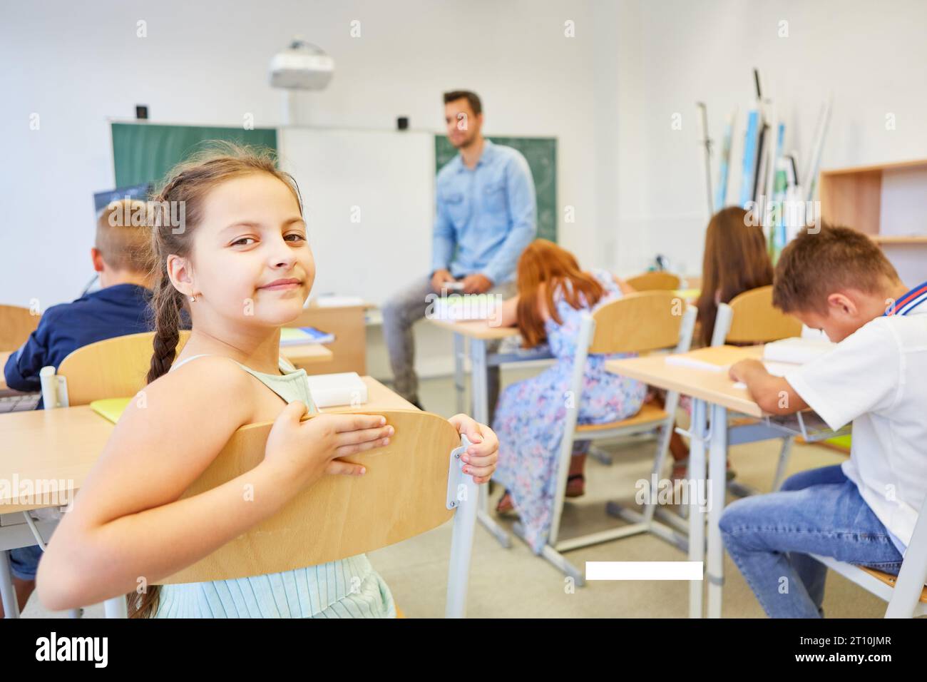 Portrait of smiling female student sitting on chair with friends in ...
