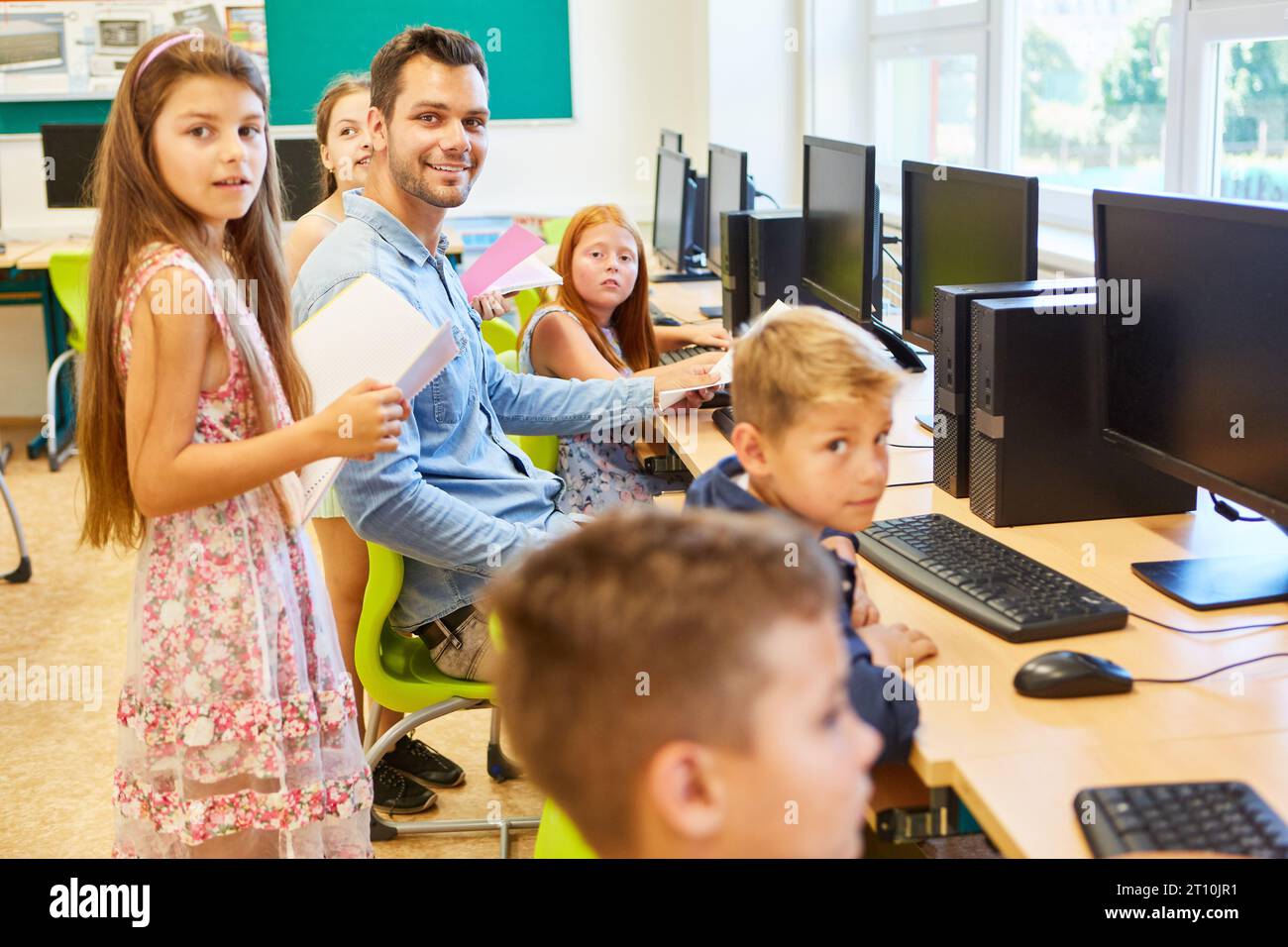 Portrait of smiling male and female students with teacher sitting in ...