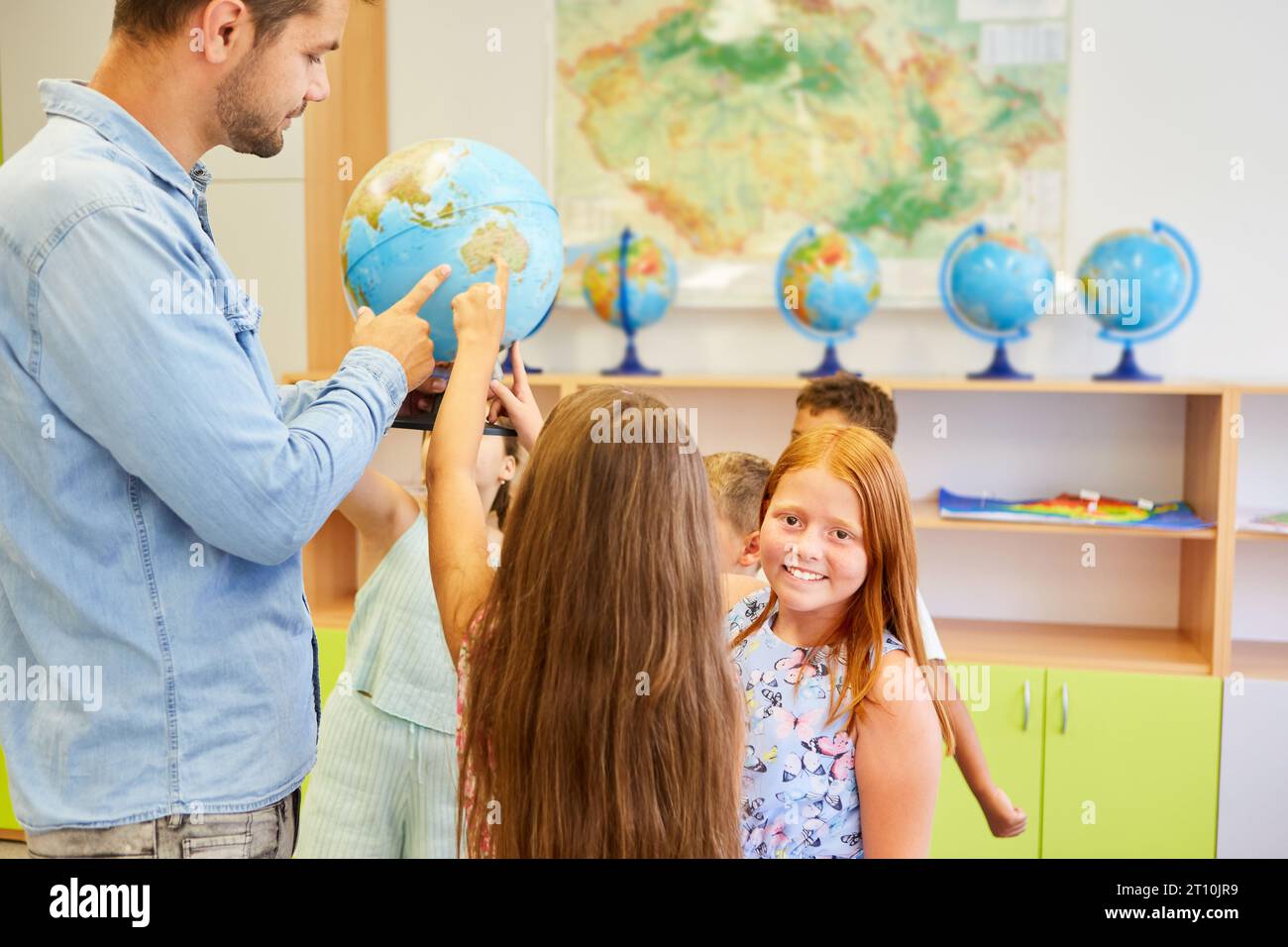 Teacher pointing globe in classroom hi-res stock photography and images ...