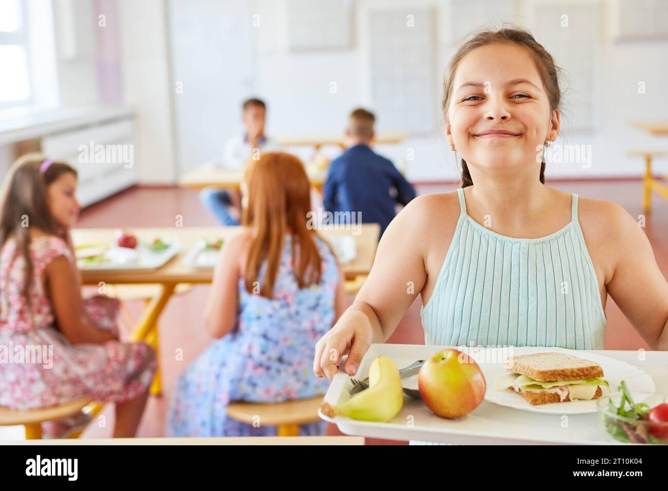 Portrait of happy girl holding healthy food tray while standing in ...