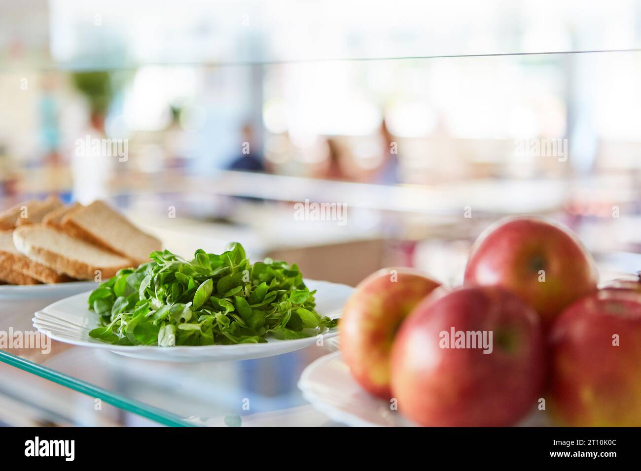 Salad leaves with apples and bread arranged in plates on shelf at ...