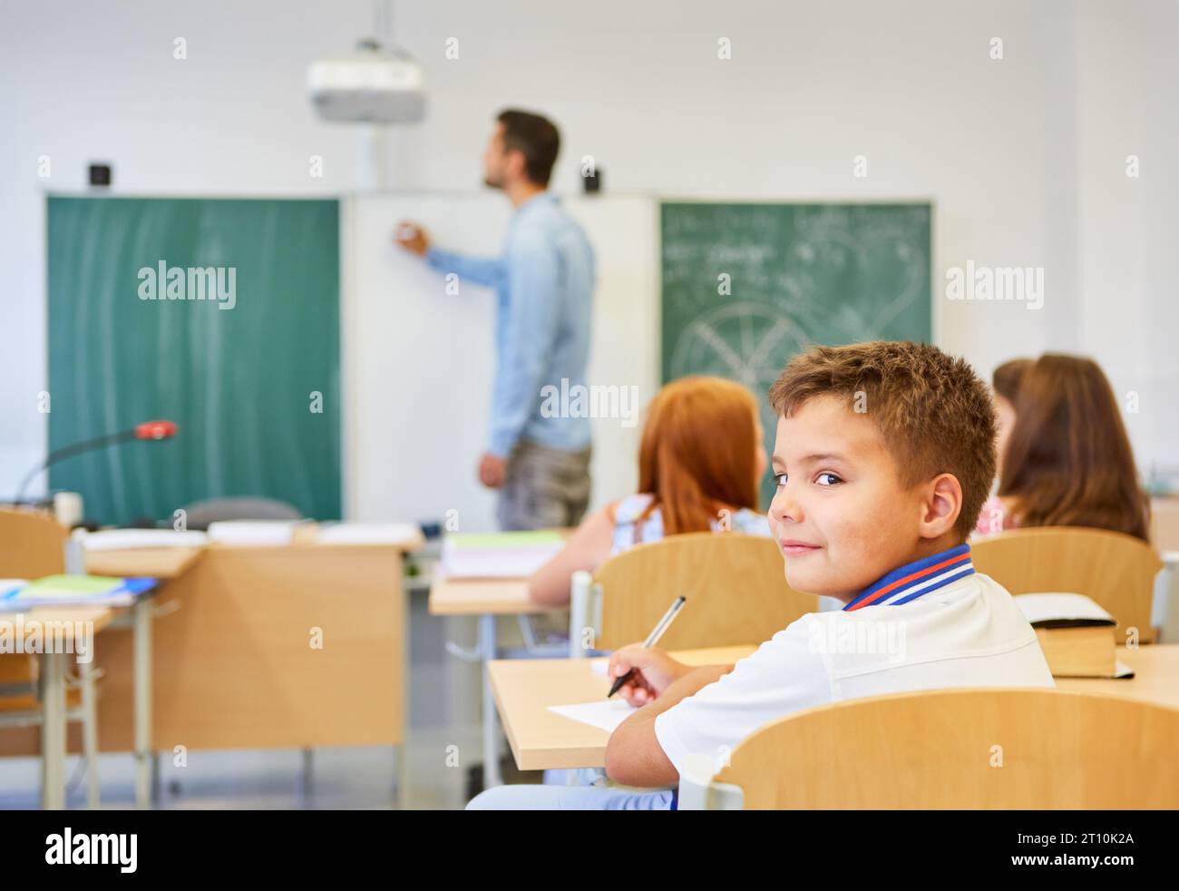 Portrait of smiling elementary male student sitting on bench during ...