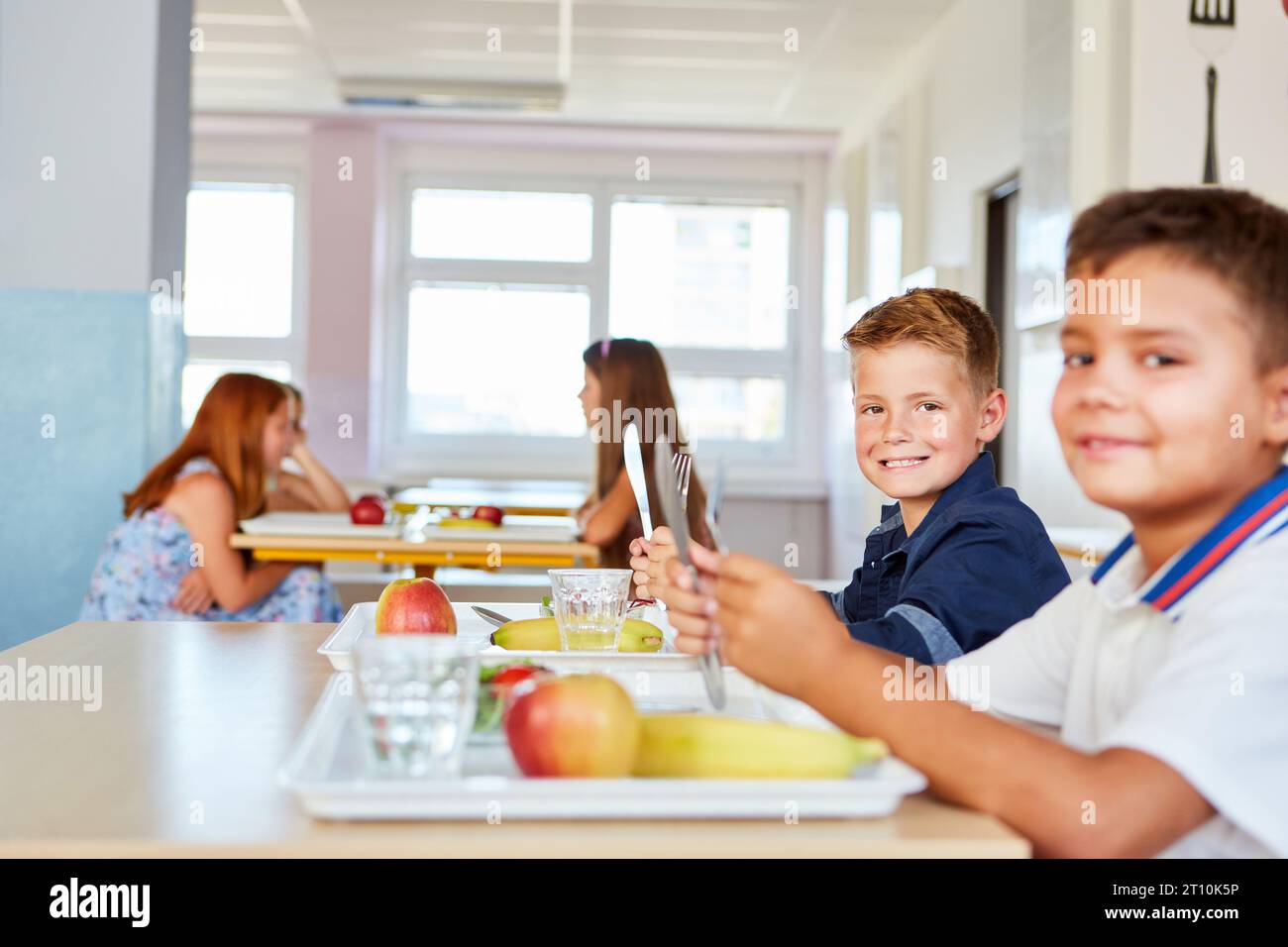Portrait of smiling male friends holding cutlery while sitting with ...